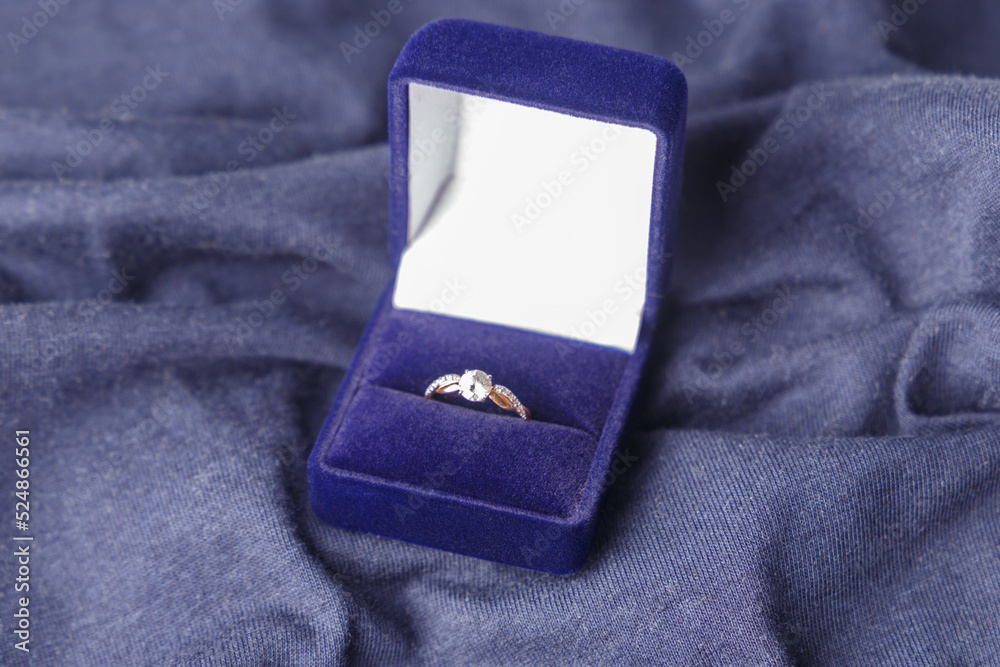 Jewelry, gold diamond ring in a blue box on a dark blue fabric ...