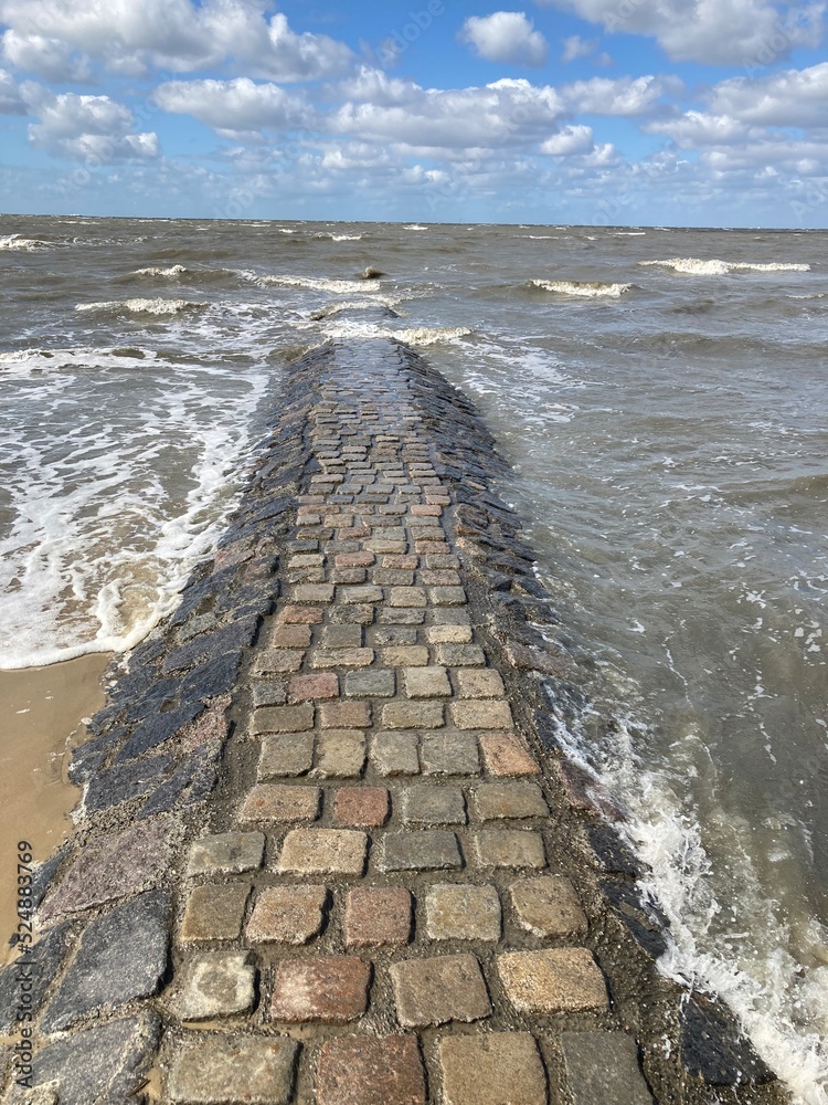 Flut trifft mit Wellen auf Buhne an der Nordsee am Strand von Cuxhaven ...