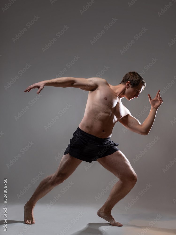 Muscular man in an artistic pose, portrait on a gray background. An ...