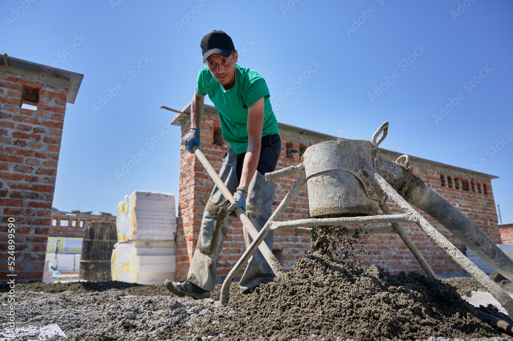 Full length of man builder shoveling sand-cement mix while working ...