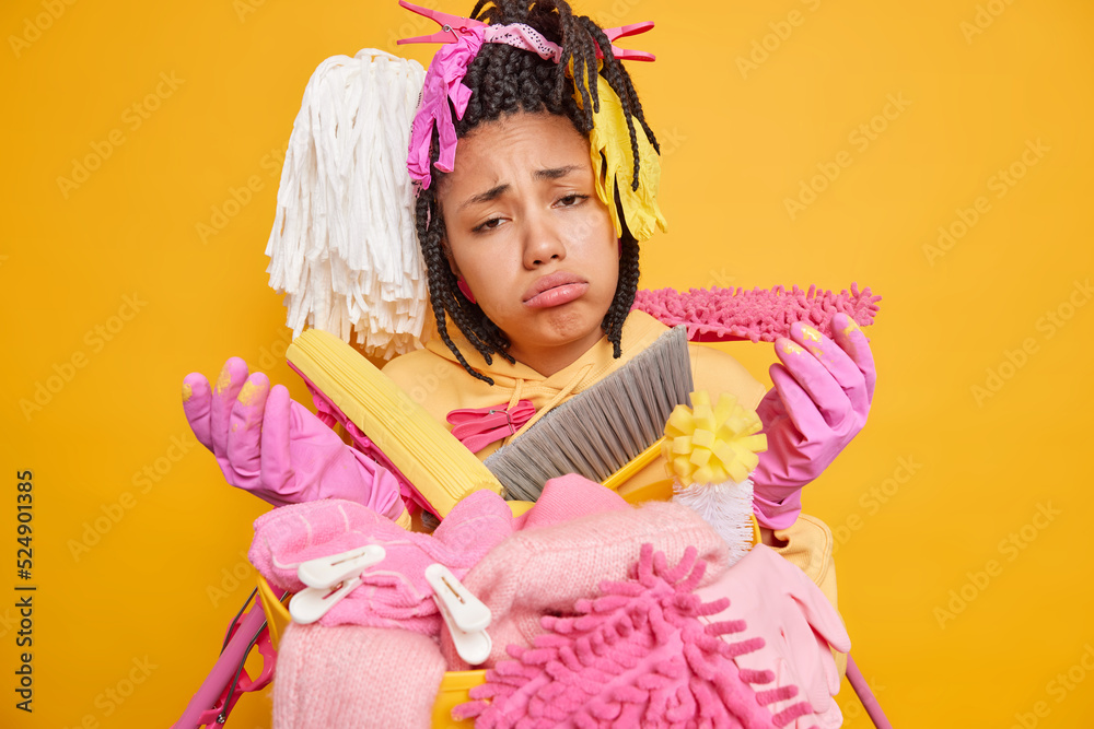 Upset tired woman has displeased sad expression after cleaning house ...