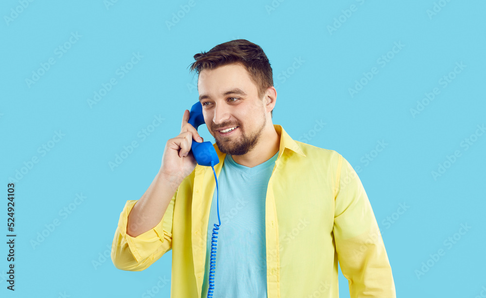 Smiling young man talk on landline phone with customer support service ...