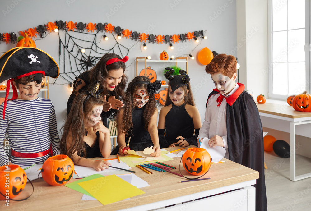 Preparing for Halloween at school. Young female teacher with her ...
