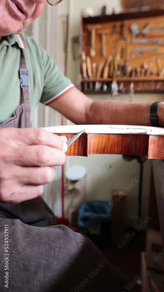 luthier carving the shape of the outside of the front of a violin with ...