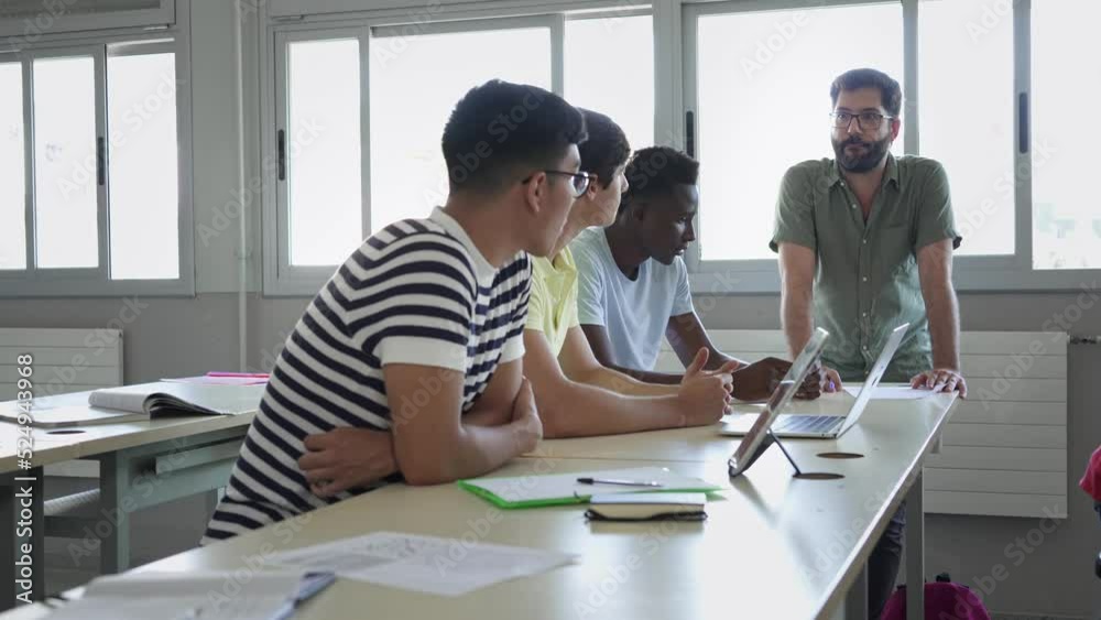 Young Professor helping multi ethnic male students in High School ...