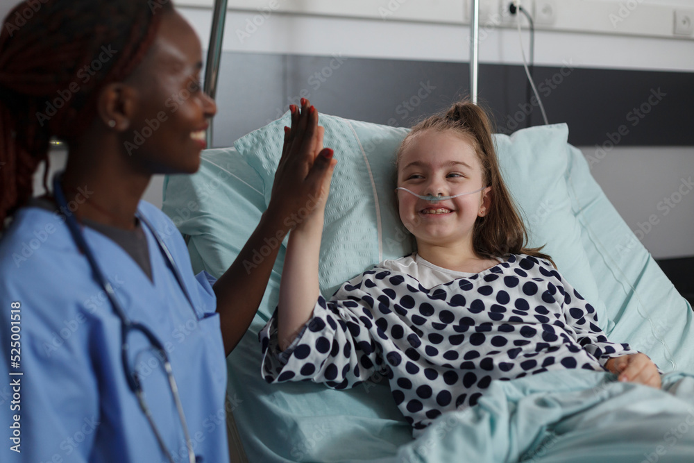 Foto de African american nurse doing high five gesture with sick girl ...