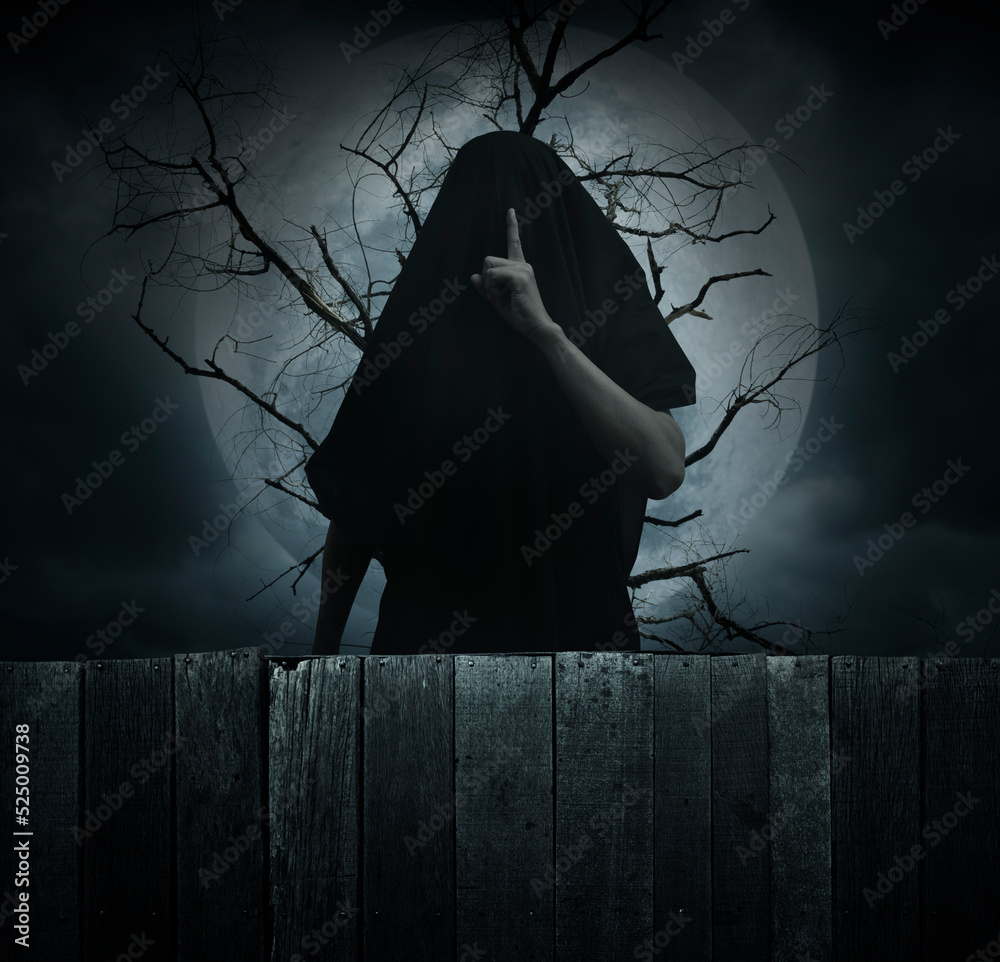 Grim reaper showing silence sign with finger standing over dead tree ...