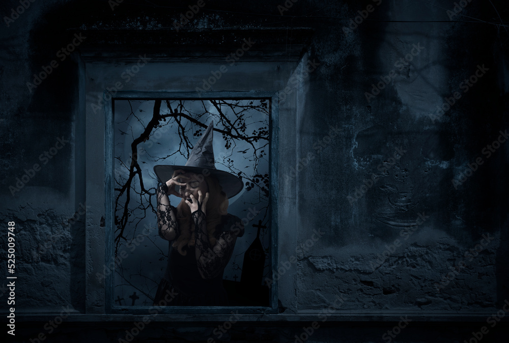 Scary halloween witch standing in old damaged window with wall over ...