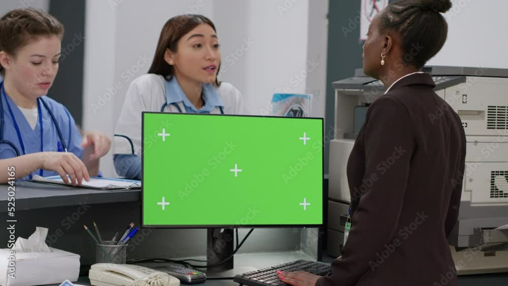 Diverse medical staff working with greenscreen on computer at hospital ...