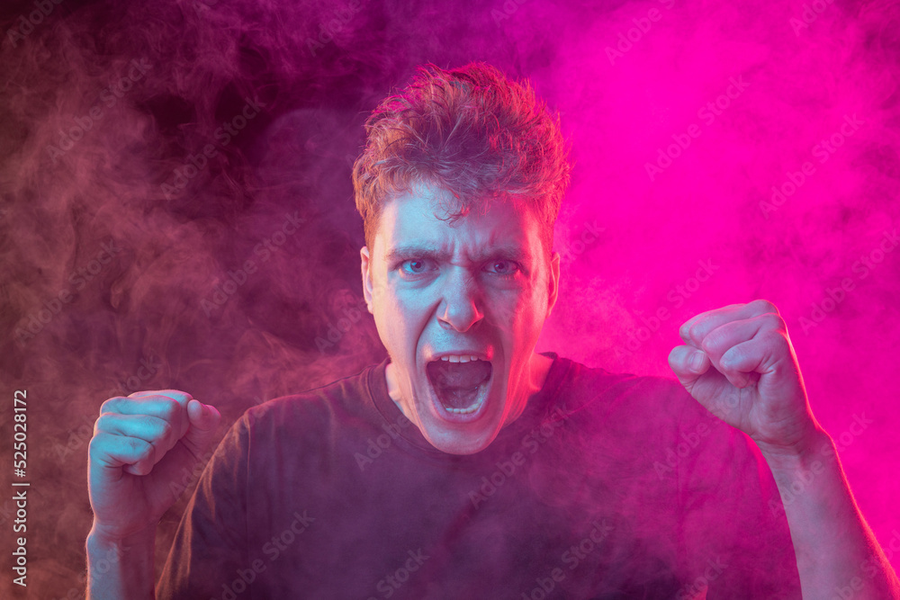 Shouting angry young man with bright emotions isolated over pink ...