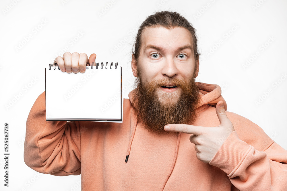 Scandinavian handsome happy man holding notepad and points to paper ...