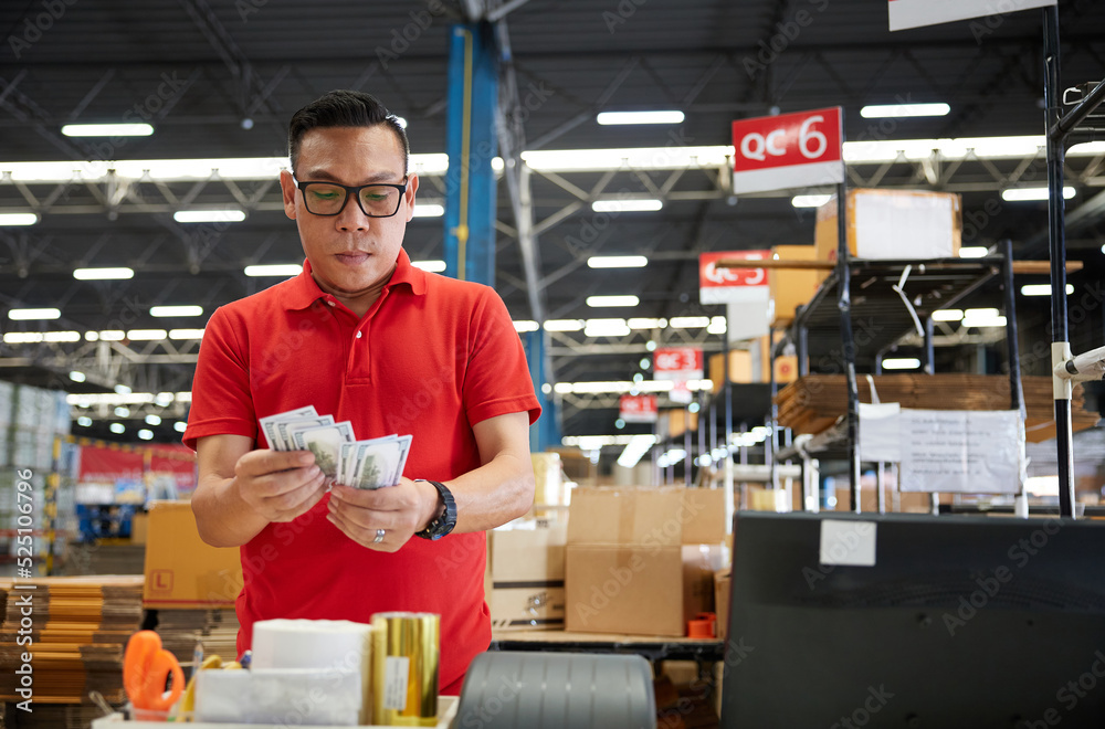factory worker or warehouser counting money in the warehouse storage ...