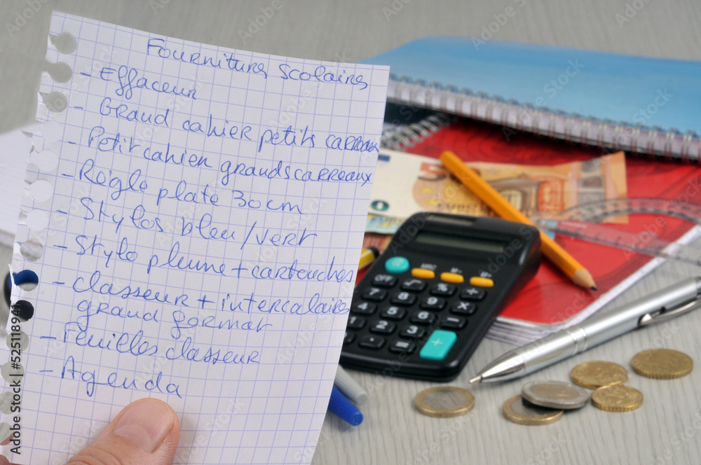 School supply shopping list in hand with school supplies in the ...