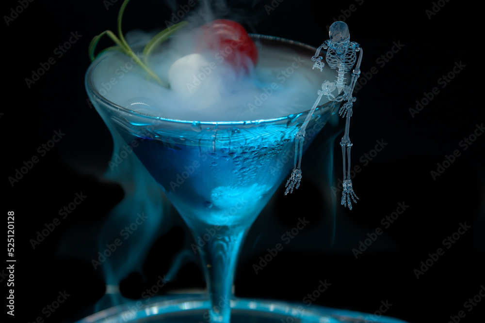 Ice human skeleton sitting on the edge of a glass with blue drink ...