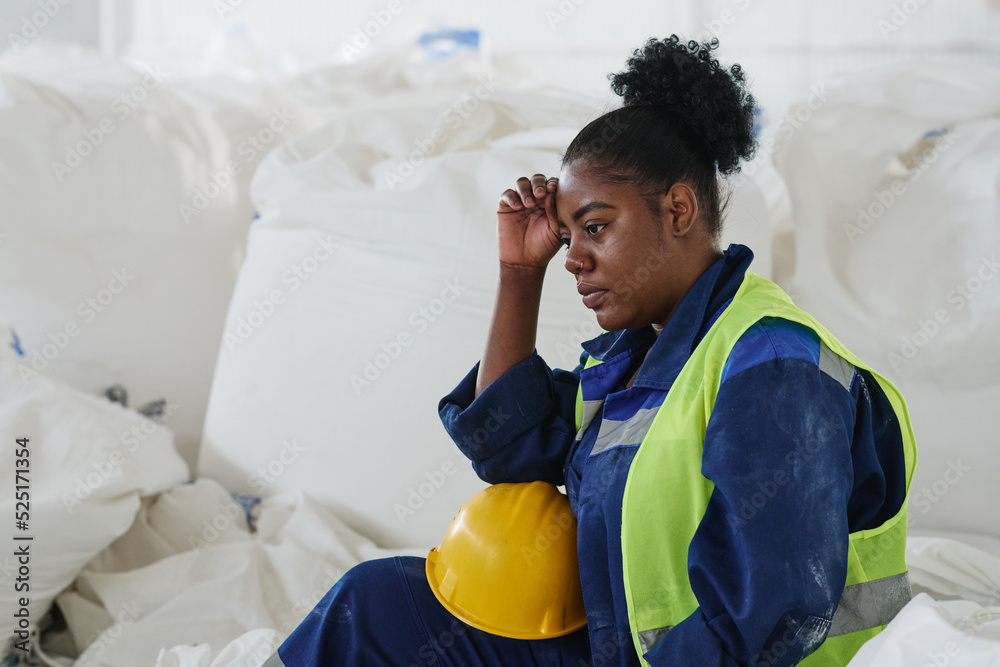 Young tired female engineer or worker of warehouse sitting by heap of ...
