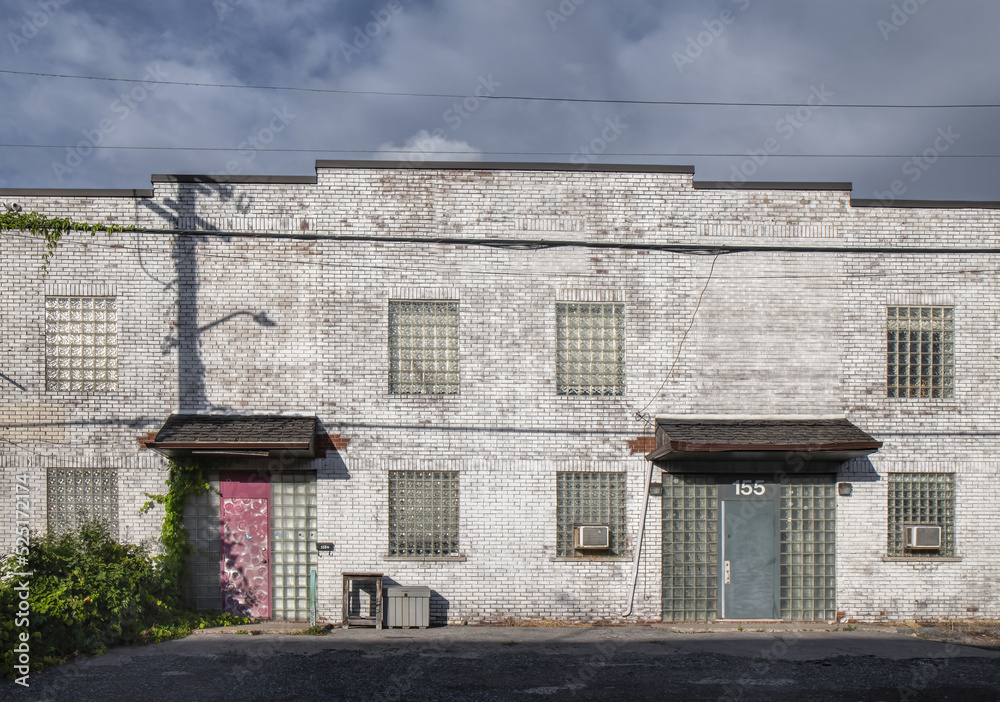 Facade of an abandoned artists studio two story white brick building ...