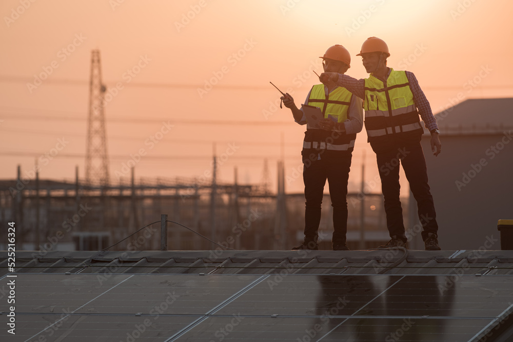 silhouette of couple worker on solar roof at sunset. Service Engineers ...