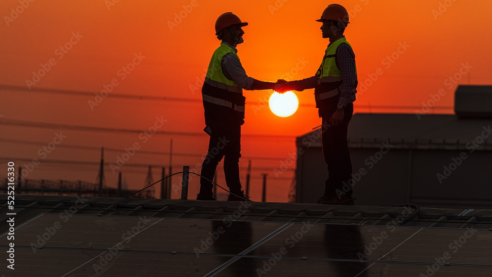 silhouette of couple worker on solar roof at sunset. Service Engineers ...