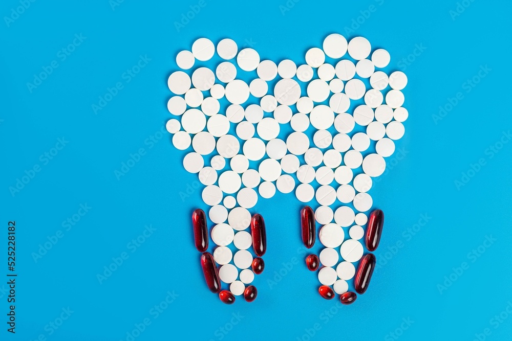 White tooth model made from pills and red capsules, concept of dental ...