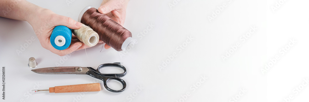 Woman holds spools of thread of different colors in her hands. There ...
