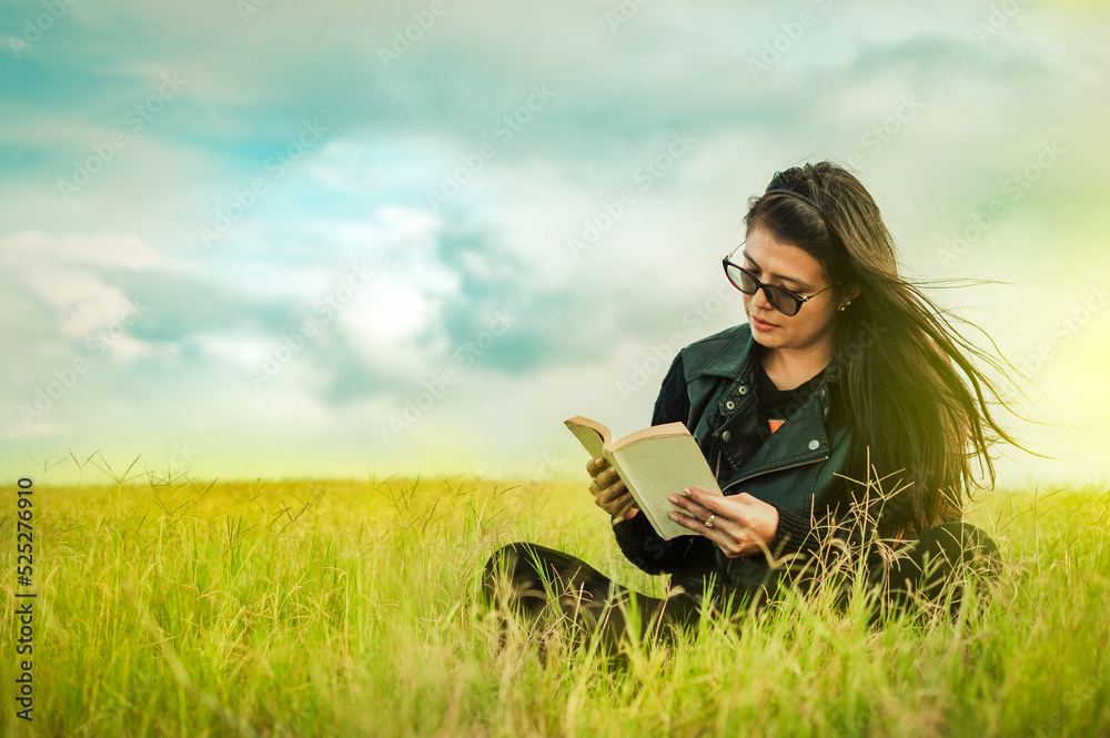 Attractive young woman reading a book in the field, Smiling girl ...