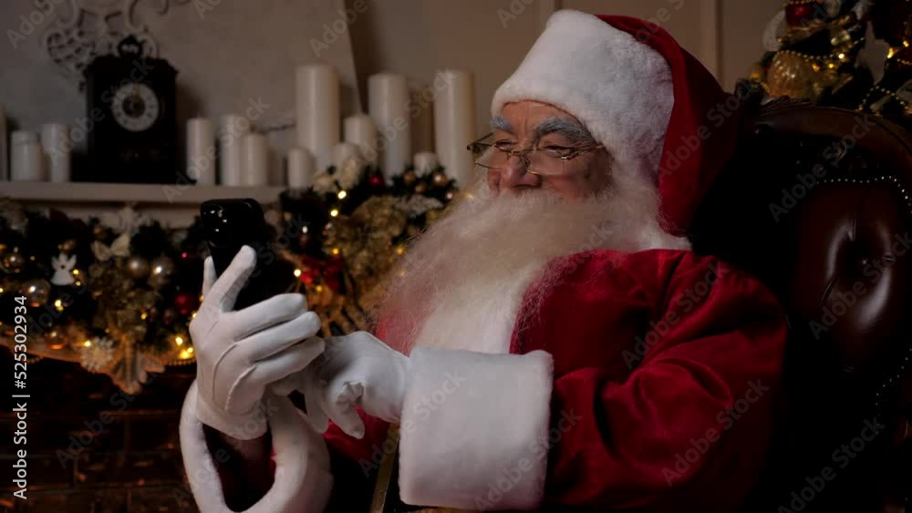 Close up modern smiling Santa Claus works on smartphone buys Christmas ...