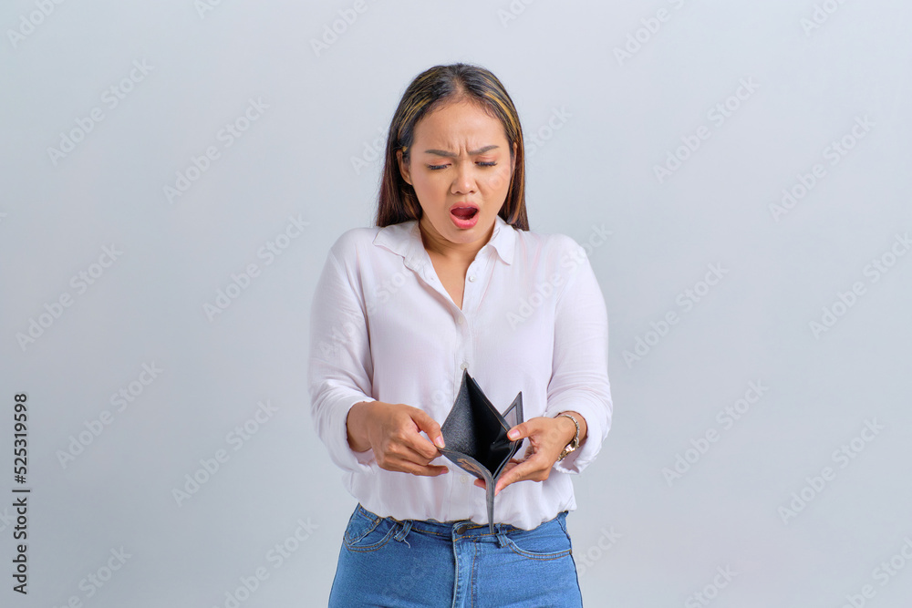 Shocked young Asian woman looking into empty wallet isolated over white ...