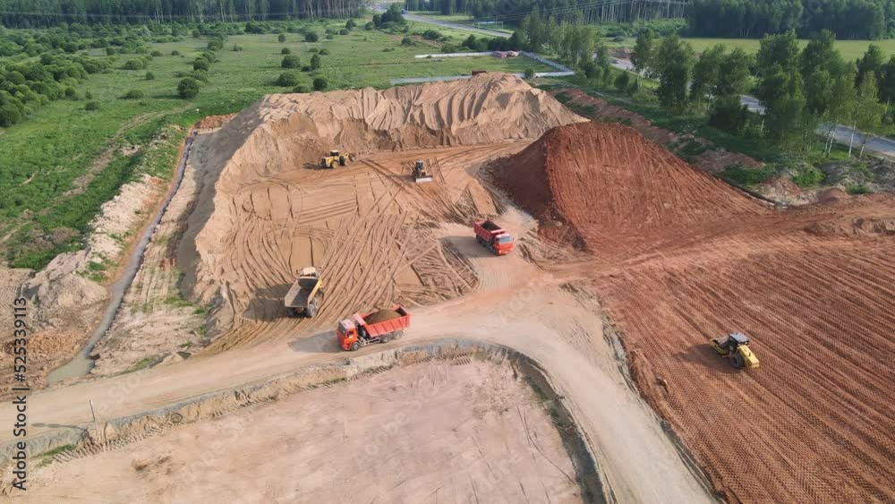 Construction machinery at an industrial site transports sand, aerial ...