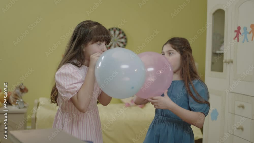 Little girls are blowing air into the balloon. Happy birthday party ...