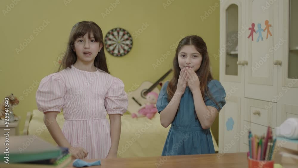 Little girls are having fun together by dancing in their room at home ...