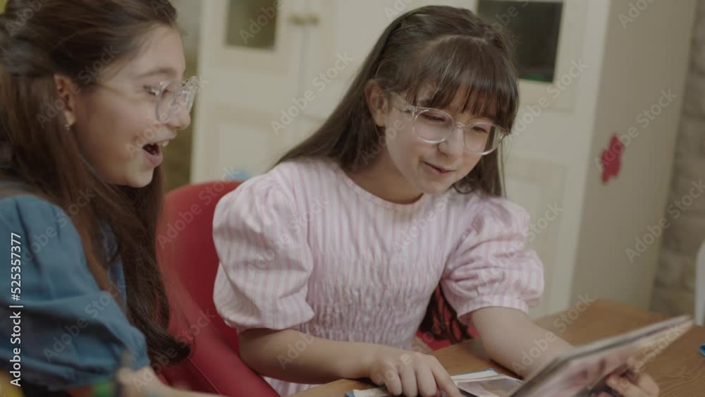 Happy cute little girls looking at photo album, remembering memories ...