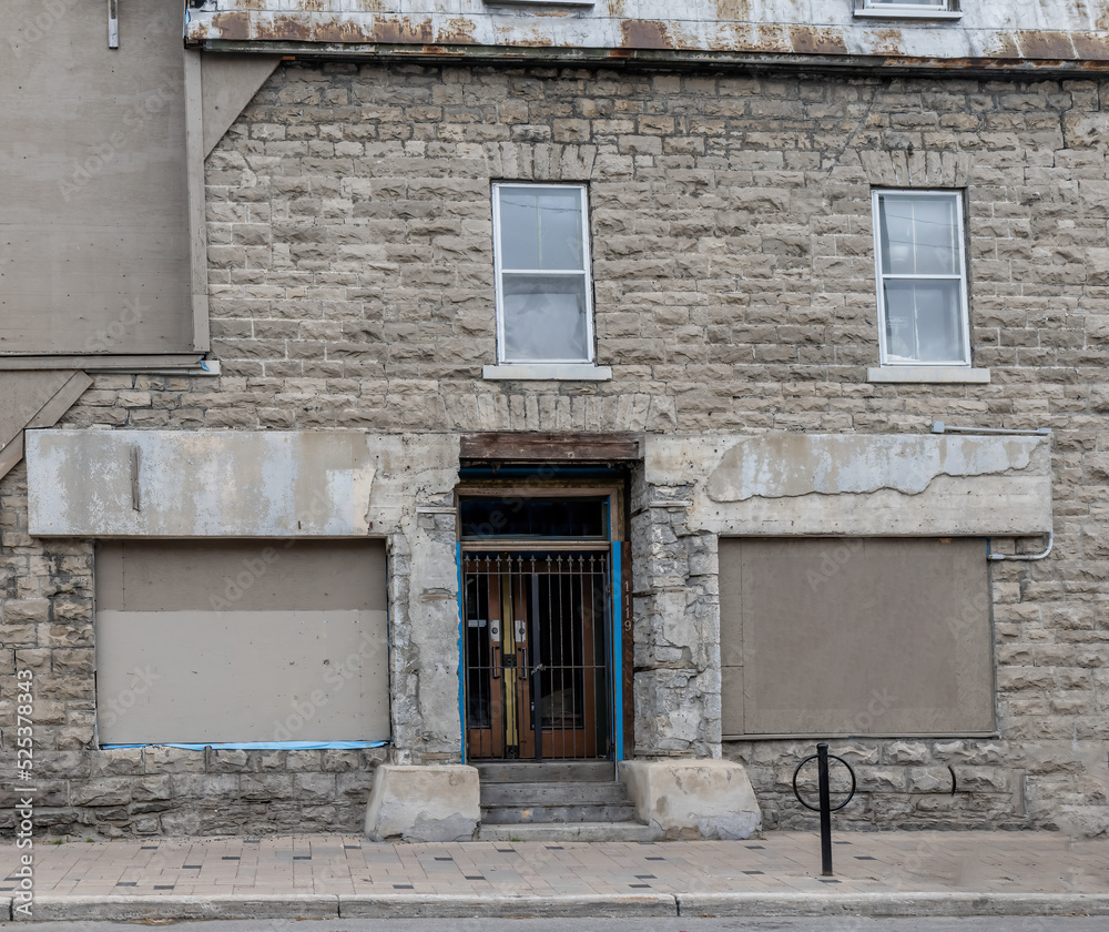 Front facade of century old stone home in poor repair and boarded up ...