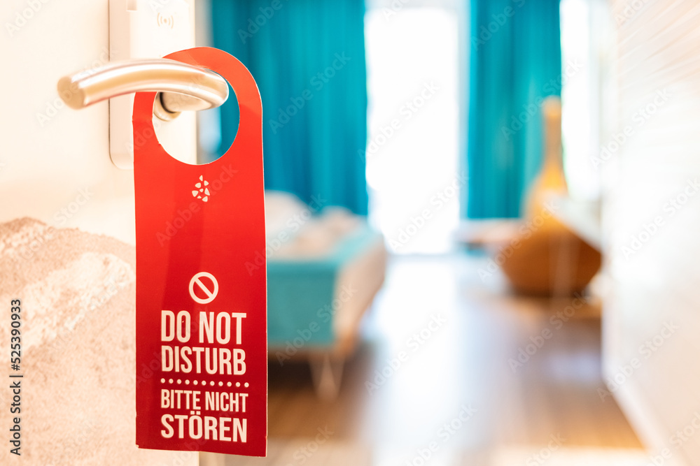 ''Do not disturb'' sign on a handle of hotel room door with bed in the ...