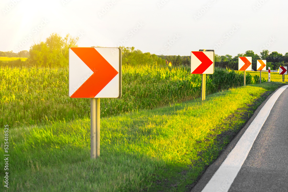 Road signs in European style warn of a sharp turn on a narrow road, a ...