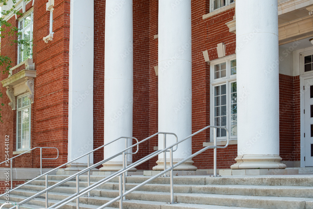 Four large white round columns at the facade entrance to a red vintage ...