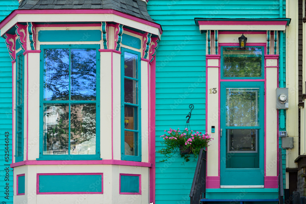 The entrance to a colorful teal green wooden building with pink and ...