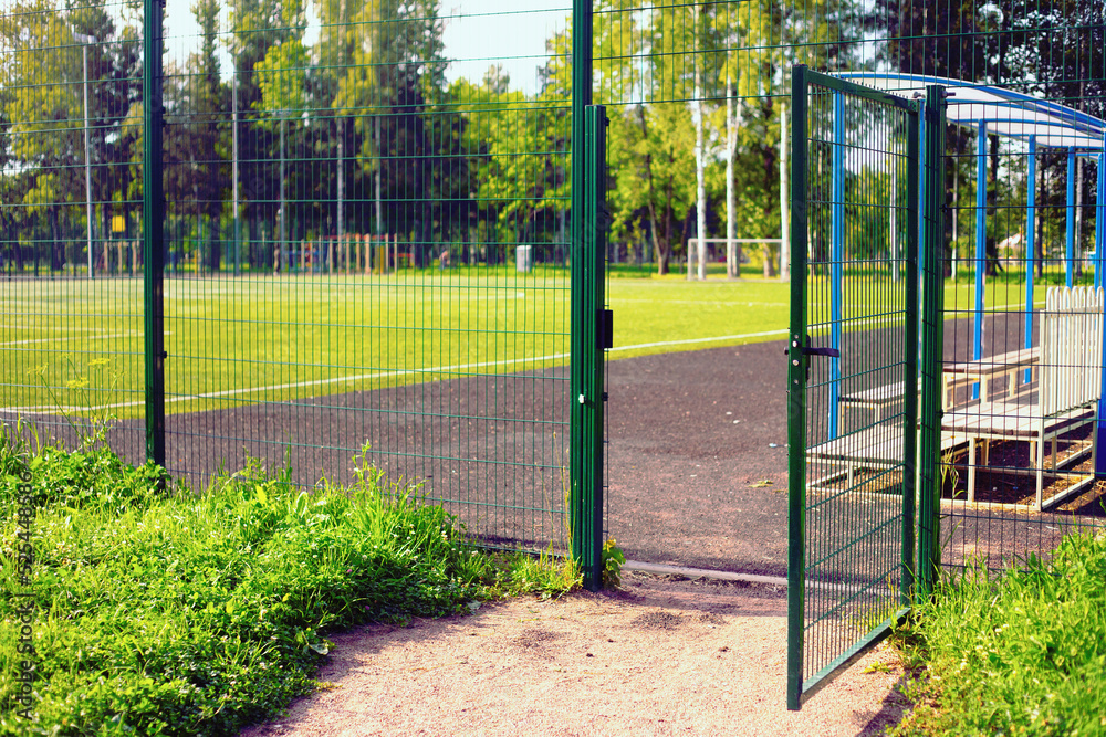 A large open metal door in a painted metal mesh fence, behind which you ...