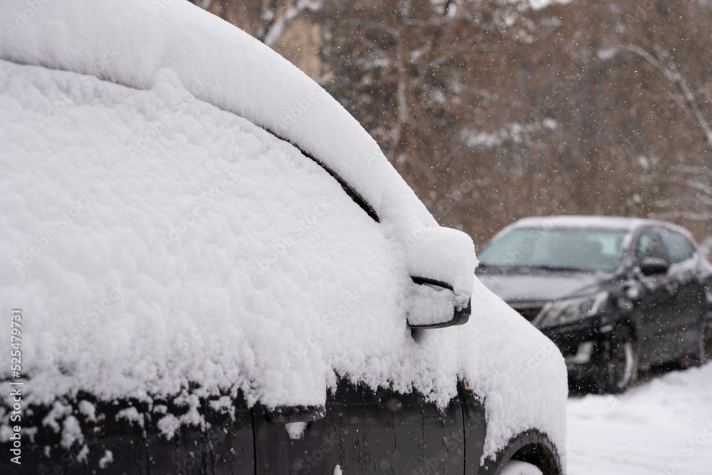 Heavy snowfall covered roads and cars. Close-up of a car in a parking ...