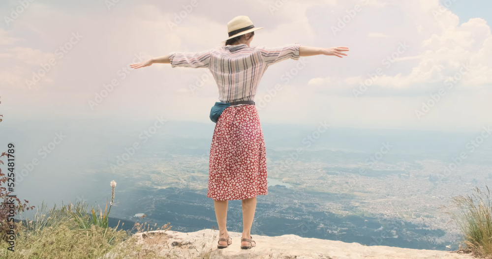 Woman traveler flaps arms like wings on mountain top. Young woman in ...