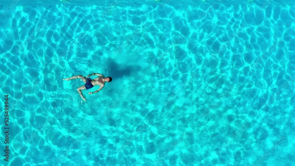 Top down aerial view of young man swims on a rippling water surface in ...