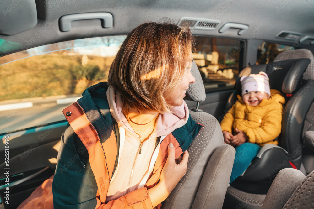 Smiling mother looking back to her cute happy little child is sitting ...