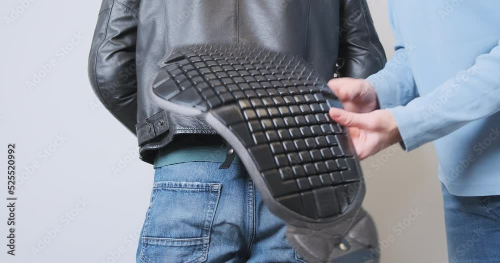 Woman tucks a plastic back protector into a standing biker's leather ...