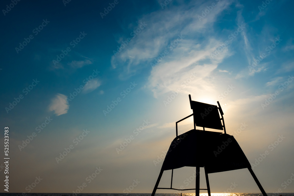Poster The dark outlines of a tall lifeguard observation chair on the ...