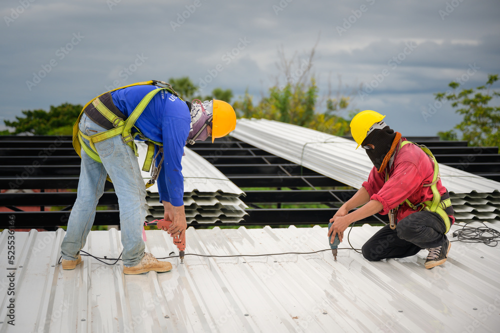 Two construction workers installing a new roof wear safety vests and ...