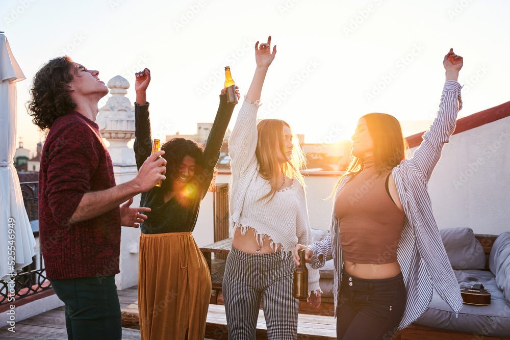 Delighted friends drinking beer and dancing on rooftop at sunset Stock ...