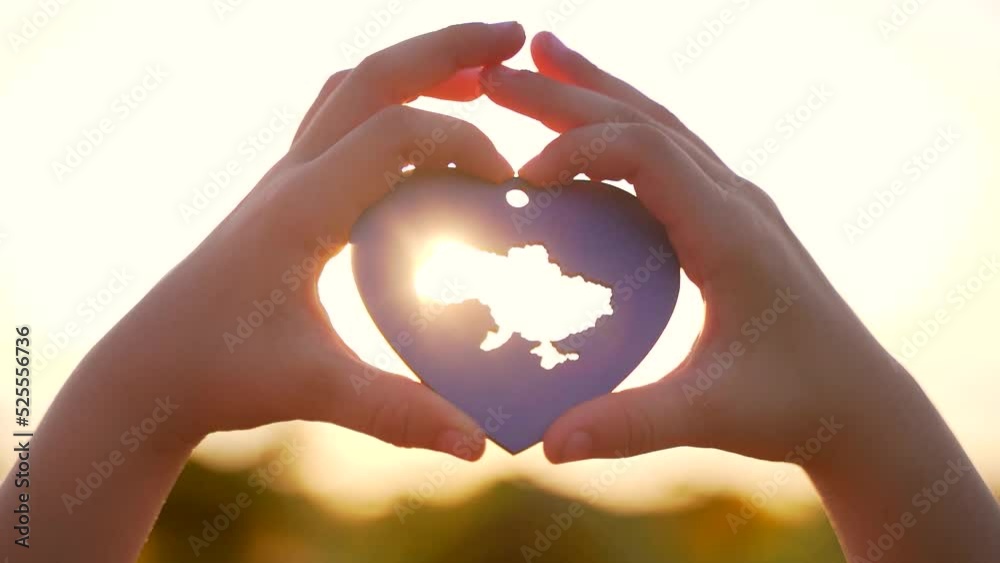 close-up girl hands holding a Ukrainian map that shines through the sun ...