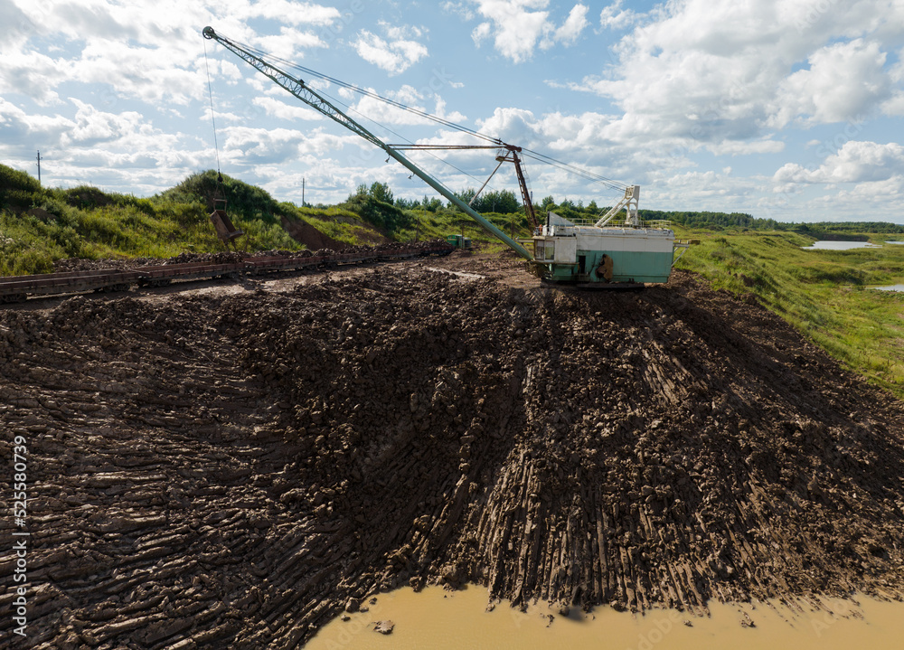 Dragline excavator works in an open pit for the extraction of clay ...