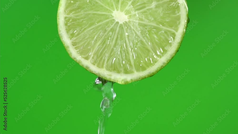 Water falling from juicy lime on green background. Lime slice and water ...