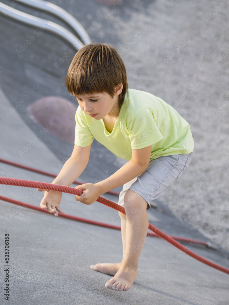 Boy climbes up a concrete slope of modern children's sports and ...