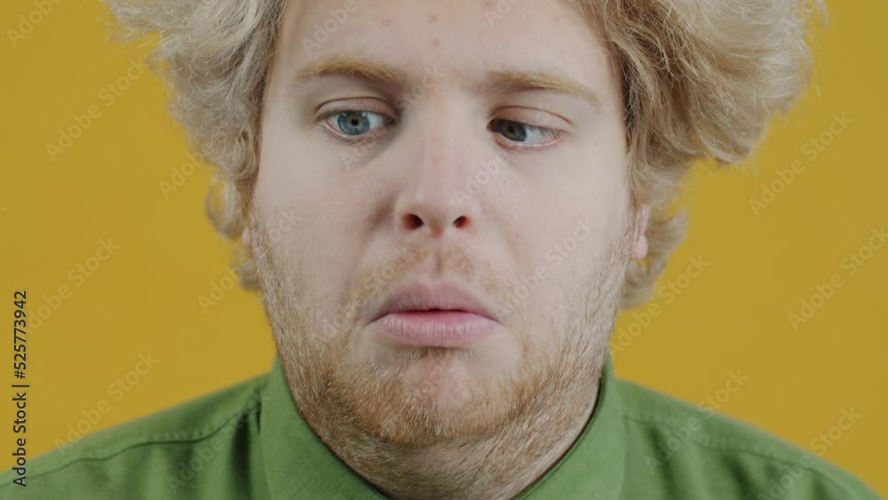 Close-up portrait of weird young guy rolling eyes and making funny ...